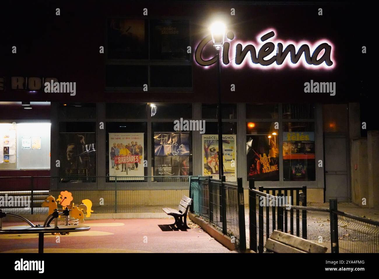 The facade of a neighborhood cinema illuminated at night, with movie ...