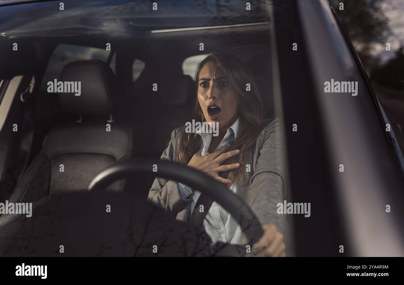 Pretty young woman driving car and having afraid and shocked face ...