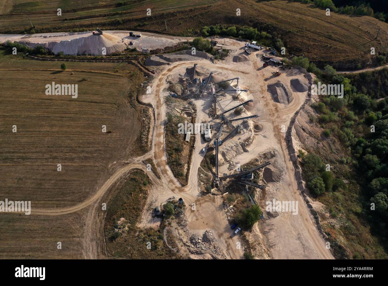 Aerial view of an excavator loading crushed stone into a dump truck in ...