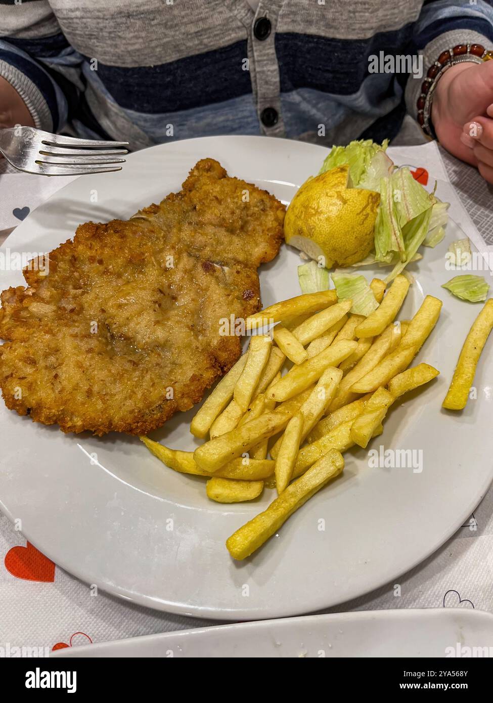 Large pork cutlet with French fries and lemon served on a plate. High ...