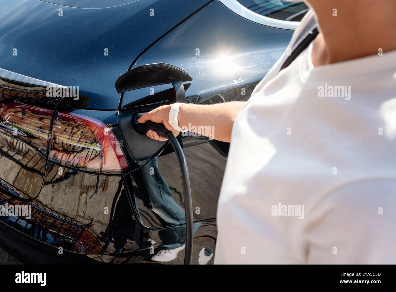 Female person charging her electric car. Woman holds EV charge ...