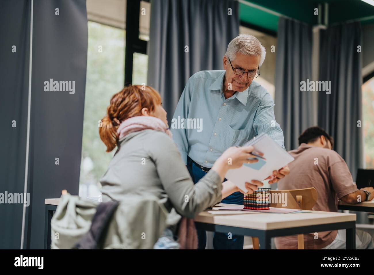 Elderly professor assisting students in a classroom setting Stock Photo ...