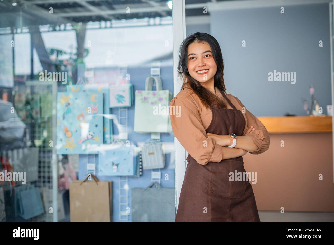 Young shopkeeper girl with hands crossed smiling happy leaning window ...