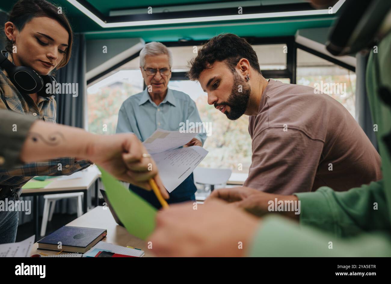 College students collaborating with professor in modern classroom ...
