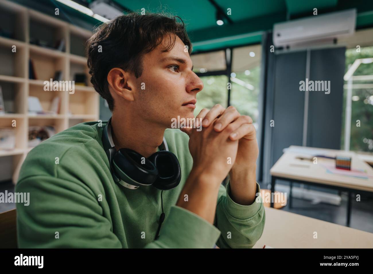 Thoughtful student in a modern classroom setting with headphones Stock ...