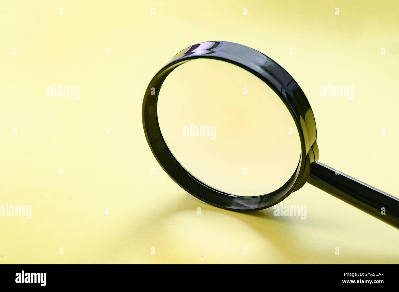 Side view of magnifying glass on yellow cover background with ...