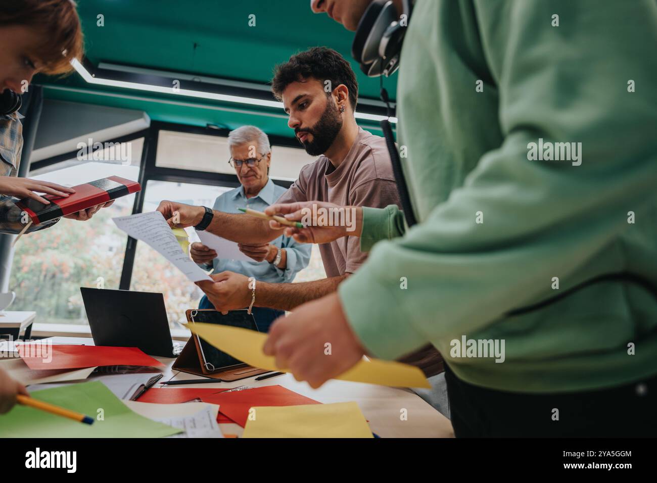 College students collaborating on a project with professor in modern ...