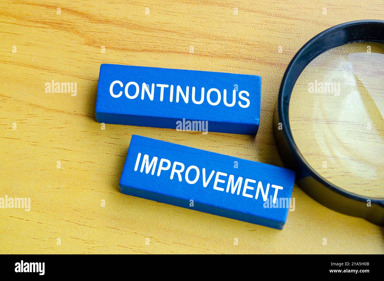 Continuous improvement text on blue wooden blocks with magnifying glass ...