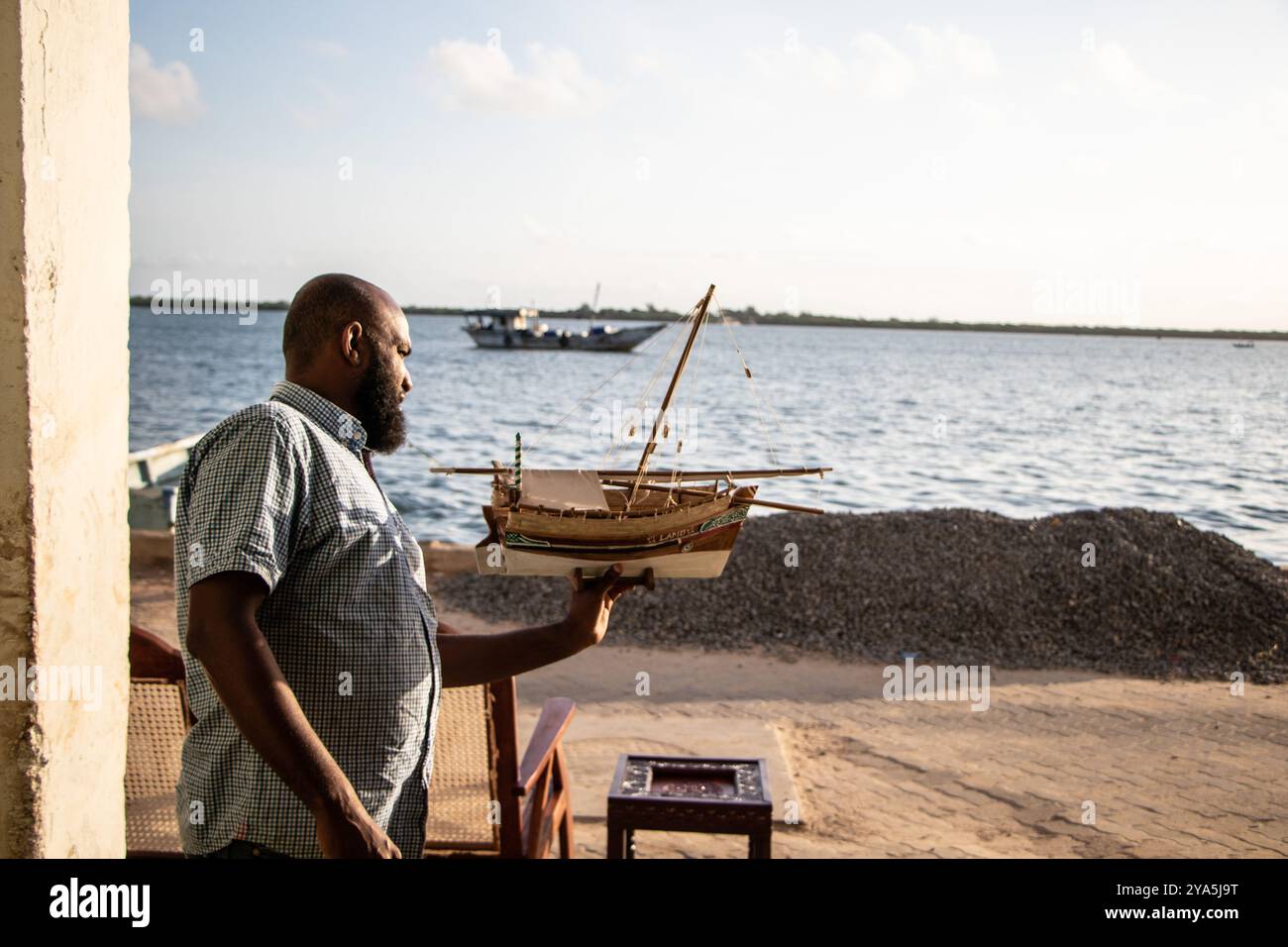 A man holds a miniature dhow at a workshop in Lamu Town. Lamu Island, a ...