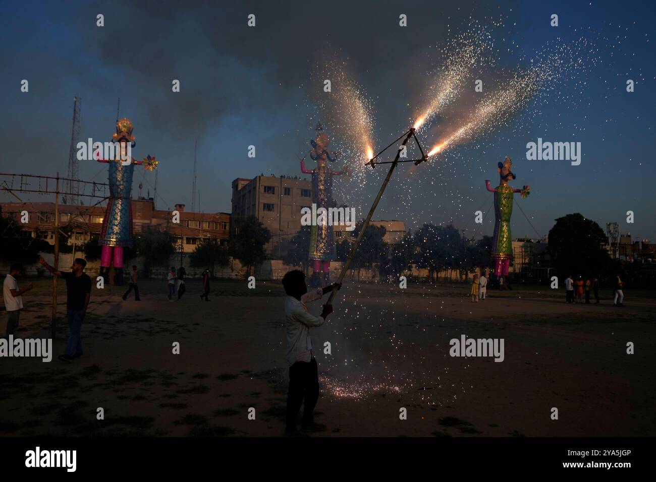 A man fires cracker near an effigy of demon King Ravana on the occasion ...