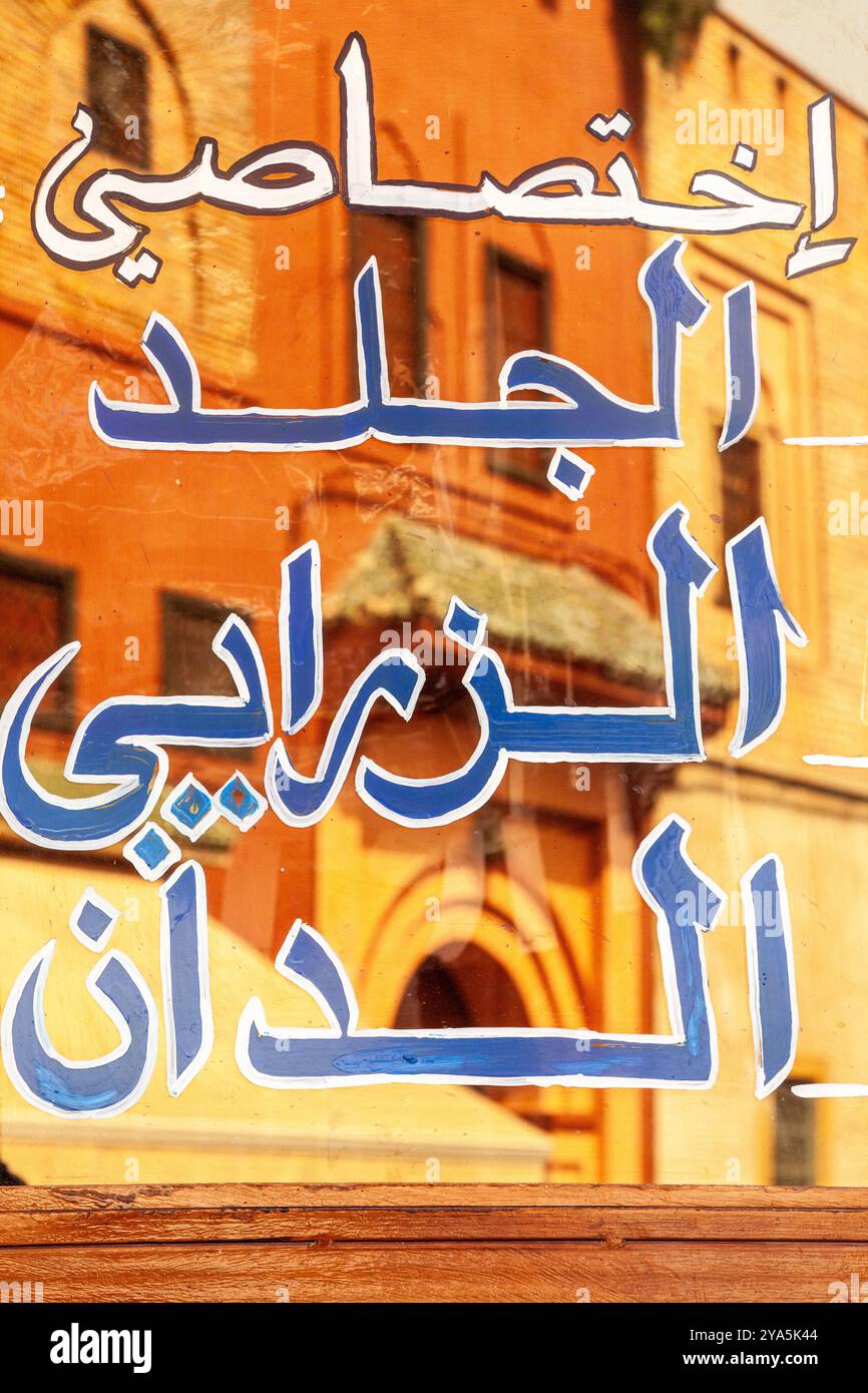 Inscription in Arabic letters on a window reflecting the surrounding ...