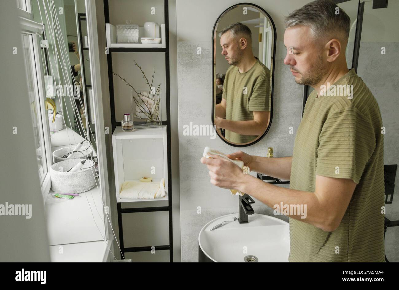 A man is drying his hands with a towel after washing them in a modern ...