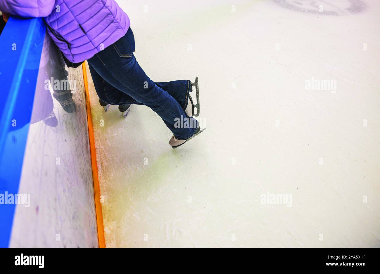Ice skater leaning against rink barrier while standing on skates ...