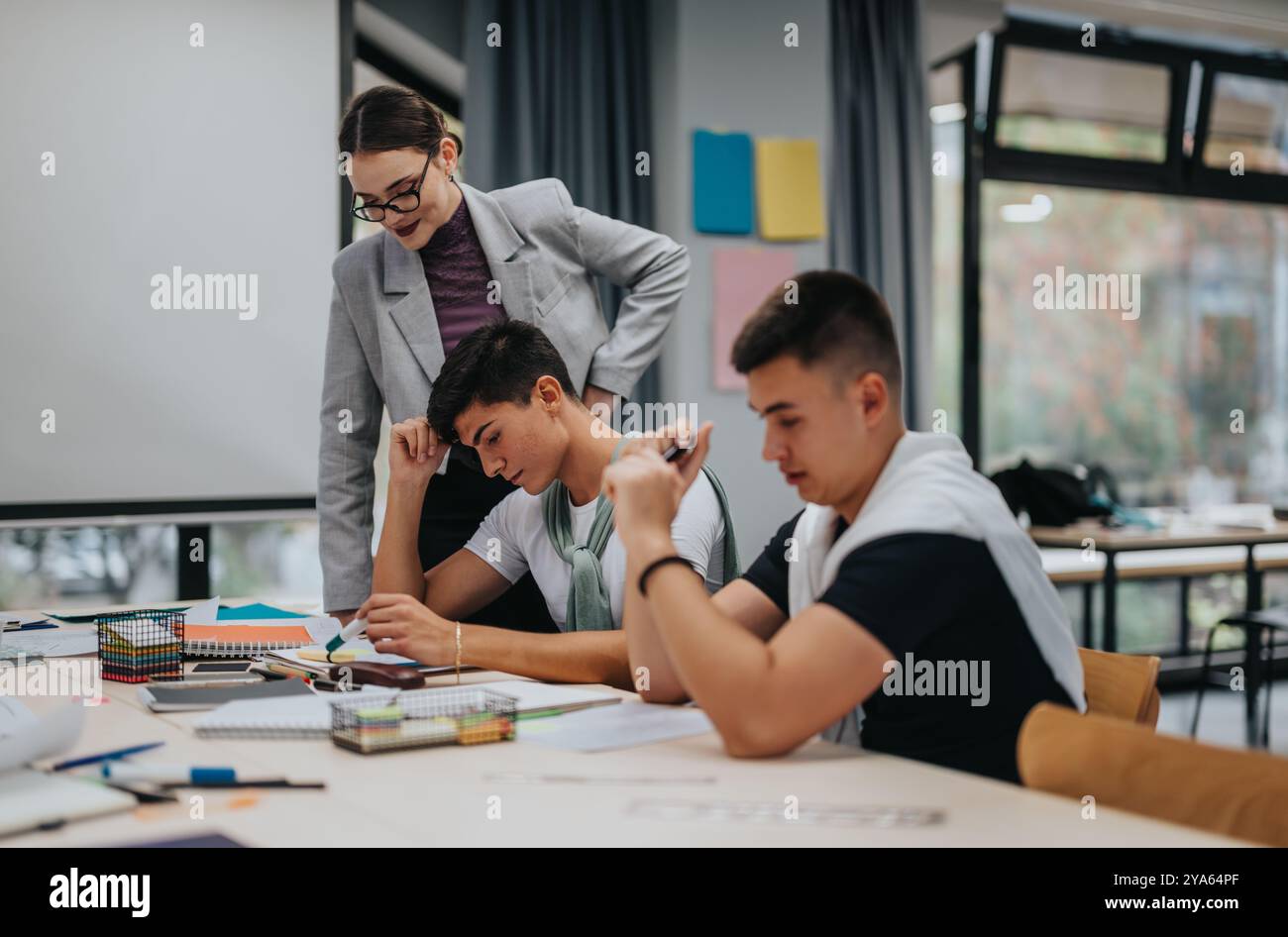 Students working together under teacher supervision in a classroom ...