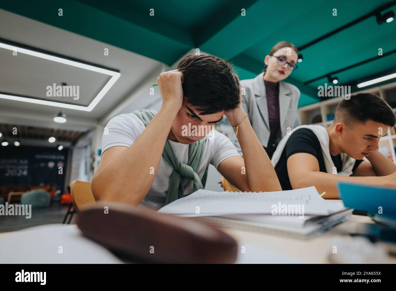 Focused students studying under teacher's supervision in modern ...