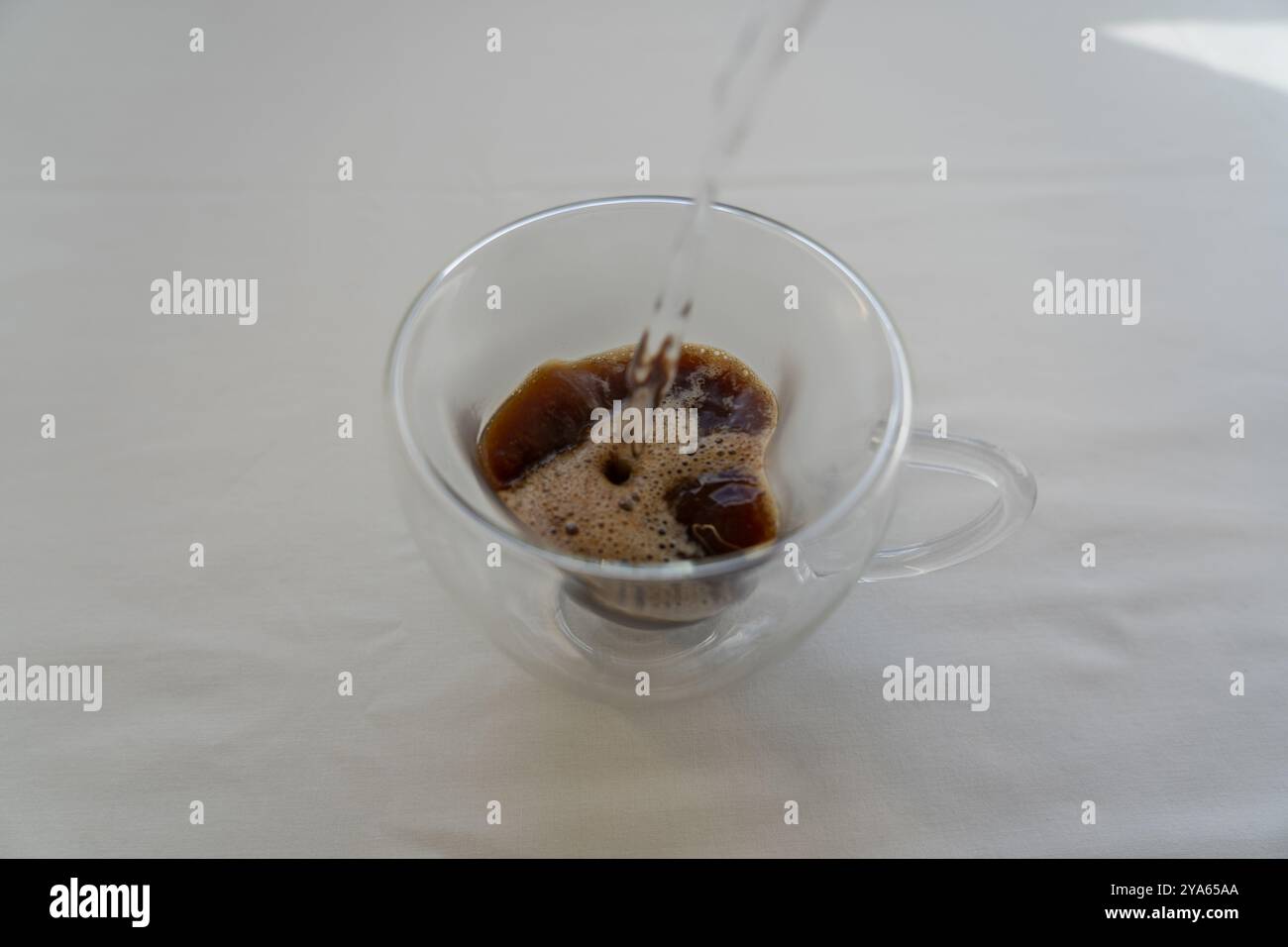 Pouring boiling water into a glass mug with instant coffee. Coffee time ...
