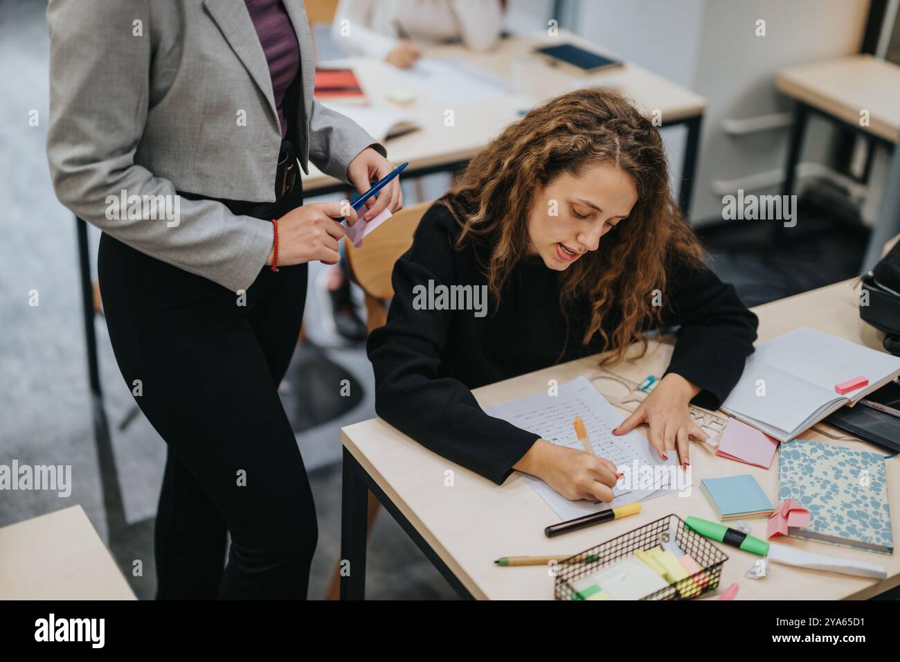 Teacher assisting student with notes in classroom setting Stock Photo ...