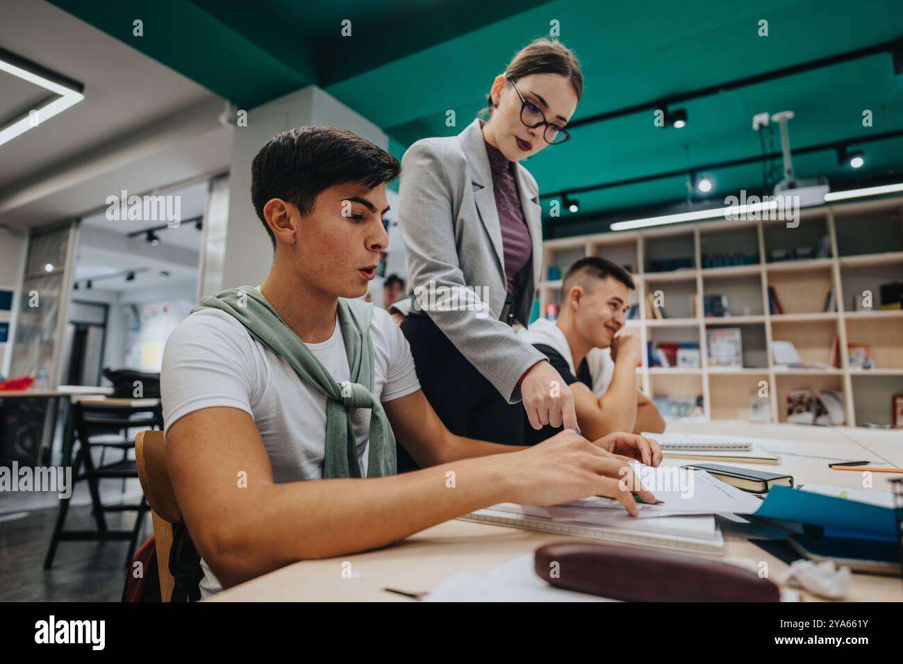 Teacher assisting focused students in modern classroom setting Stock Photo - Alamy