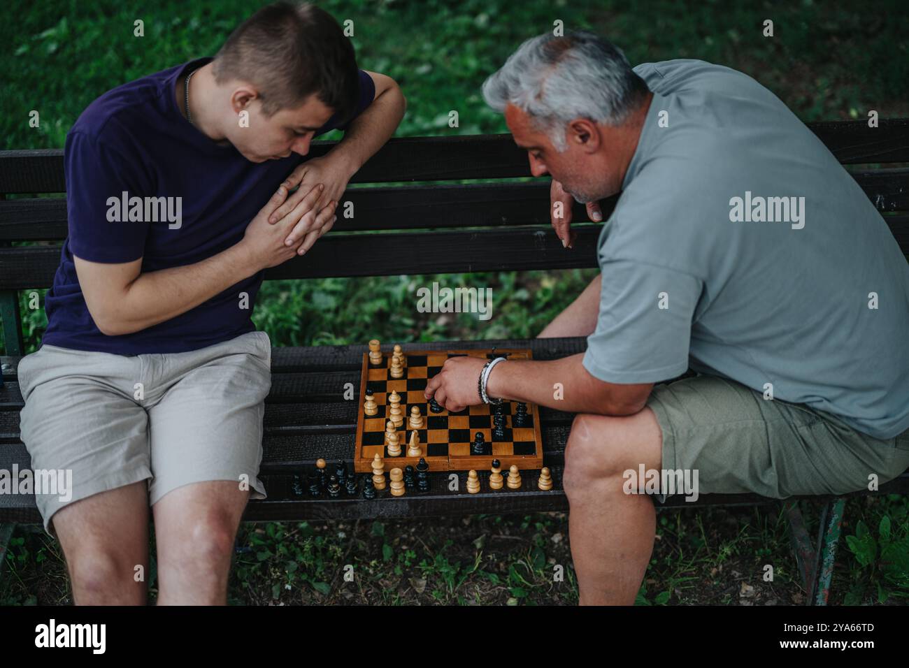 Two men enjoying a thoughtful game of chess on park bench Stock Photo ...
