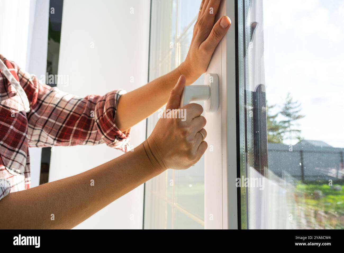The hand holds the handle of a plastic double-glazed window, closing ...