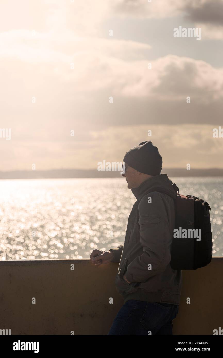 Man standing by a sea wall looking at the view, getting away from it ...