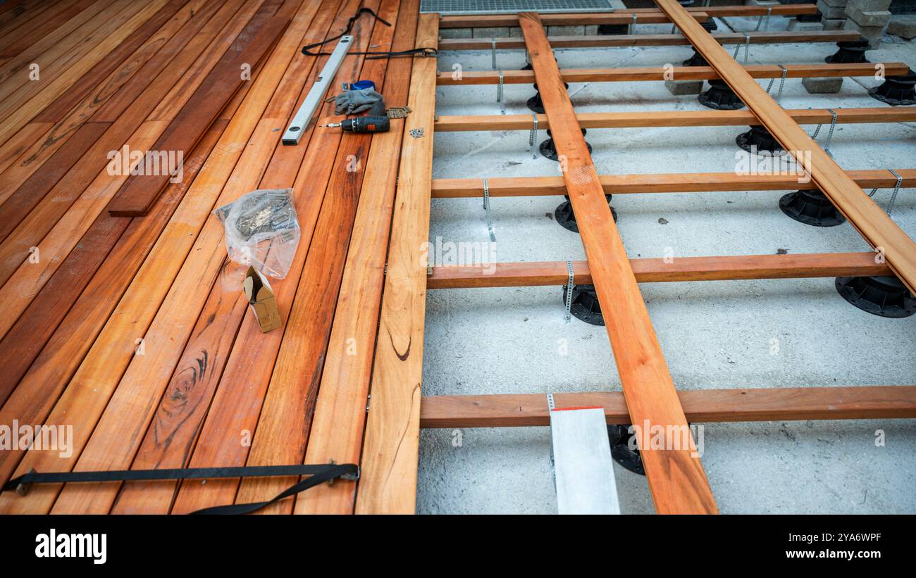 A partially built wooden deck with tools and materials scattered around ...