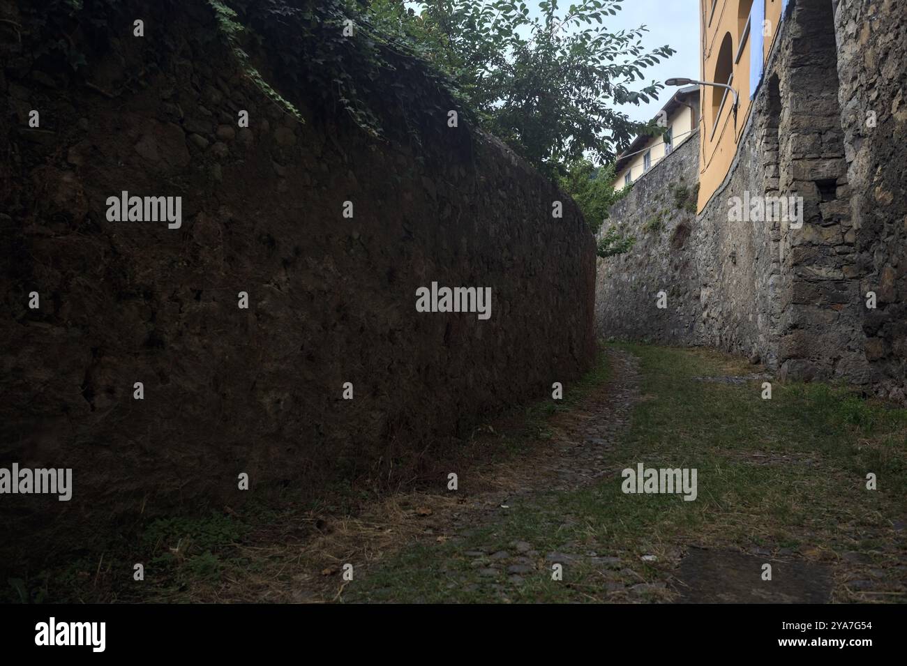 Sloppy cobbled path between a stone wall and a stone building in the ...