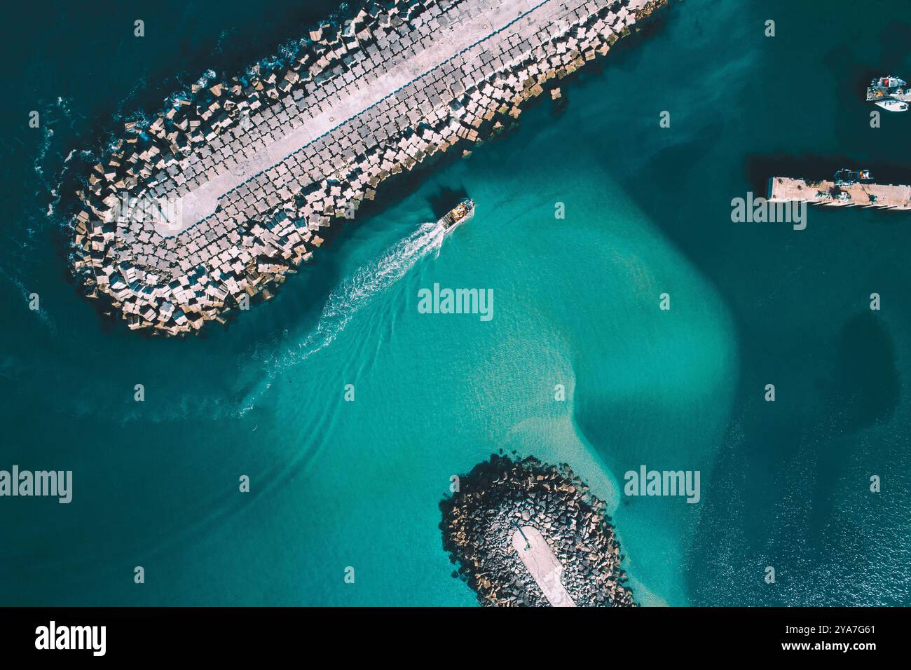 A fishing boat entering the breakwater of a seaport, top view from a ...