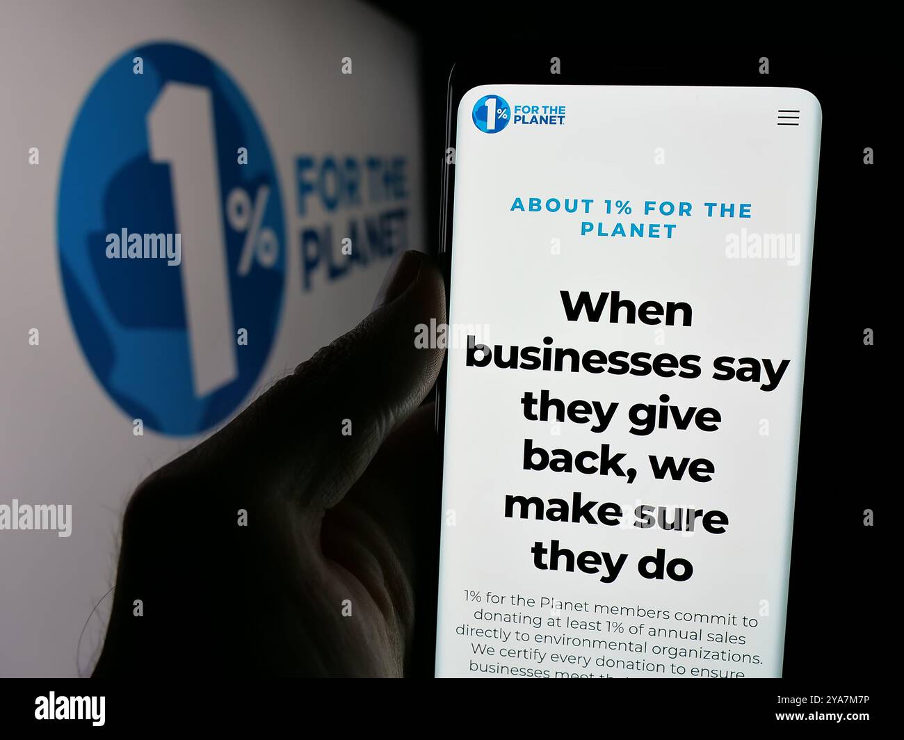 Person holding cellphone with webpage of organization One Percent for ...