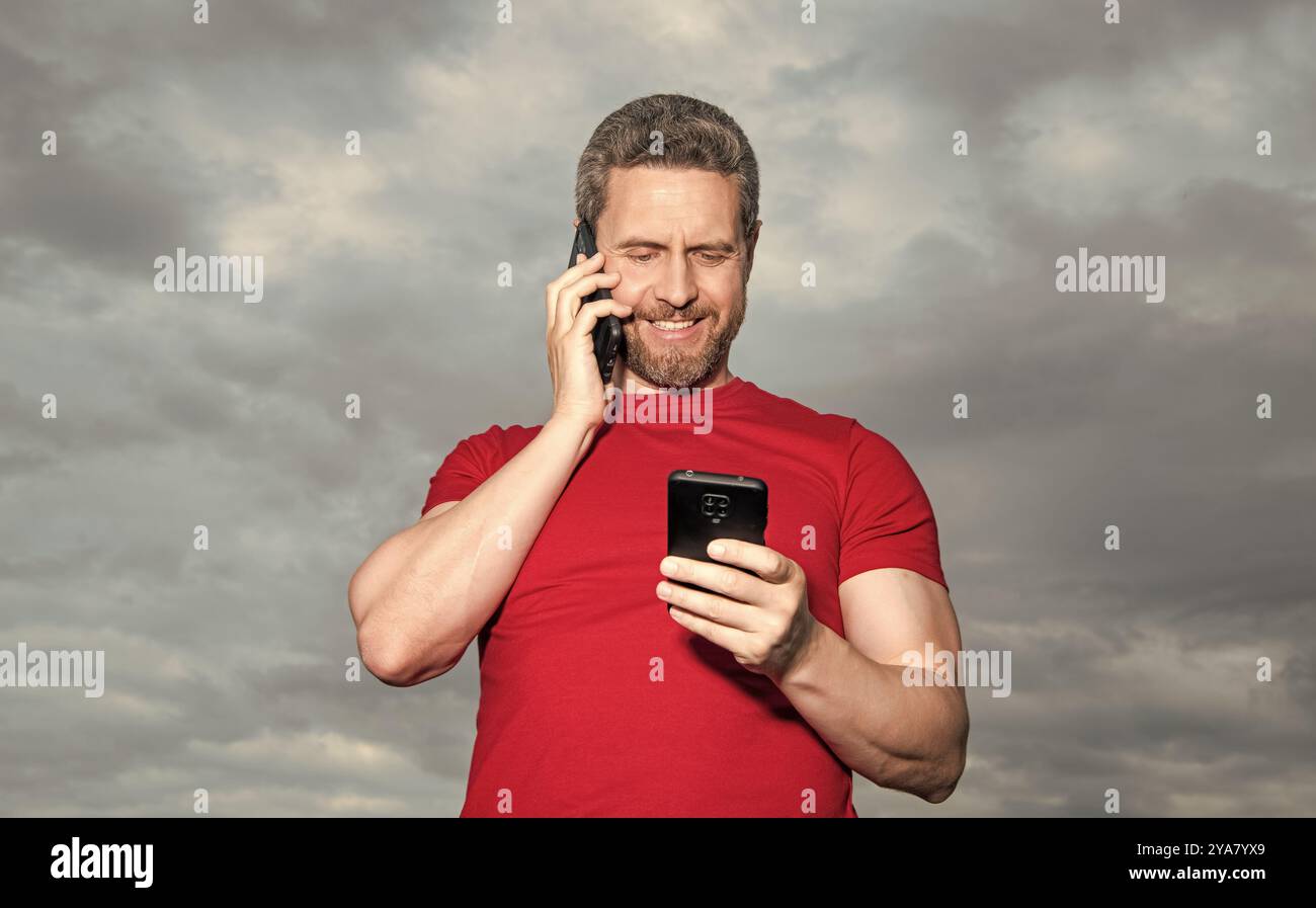positive man has phone talk on sky background. man has phone talk ...