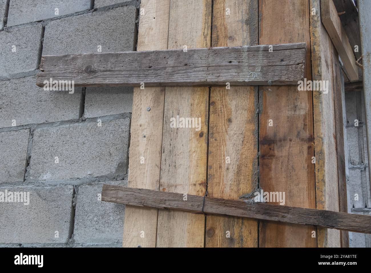 A wooden beam is attached to the wall of a house under construction ...