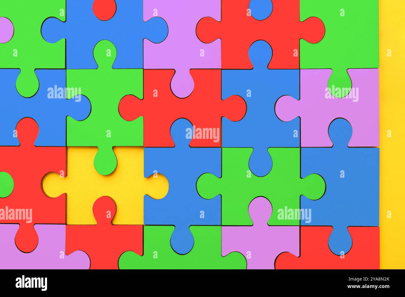 Many colorful puzzle pieces on yellow background, top view. Symbol of ...