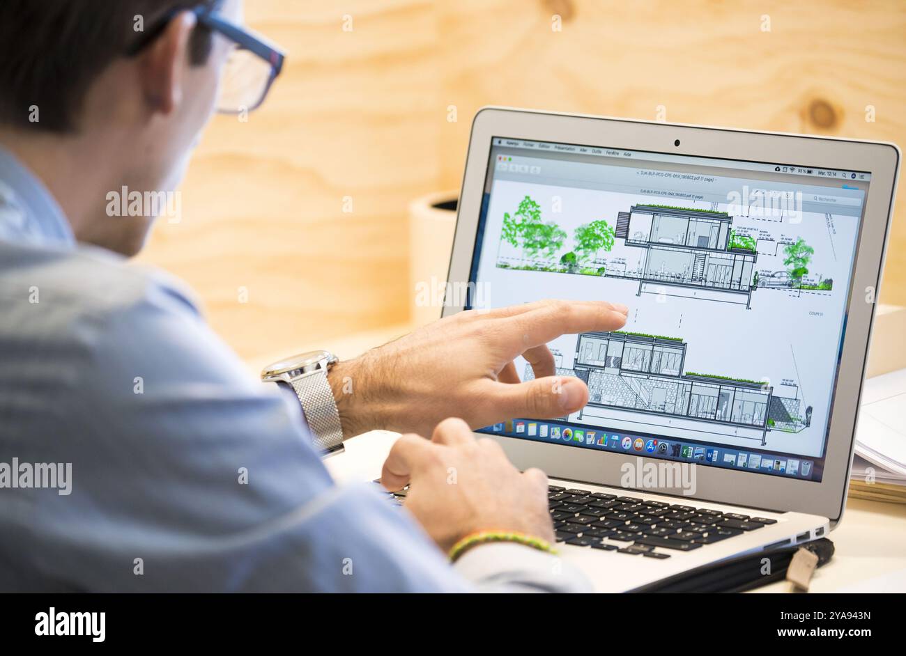 An architect is meticulously reviewing modern building plans and ...
