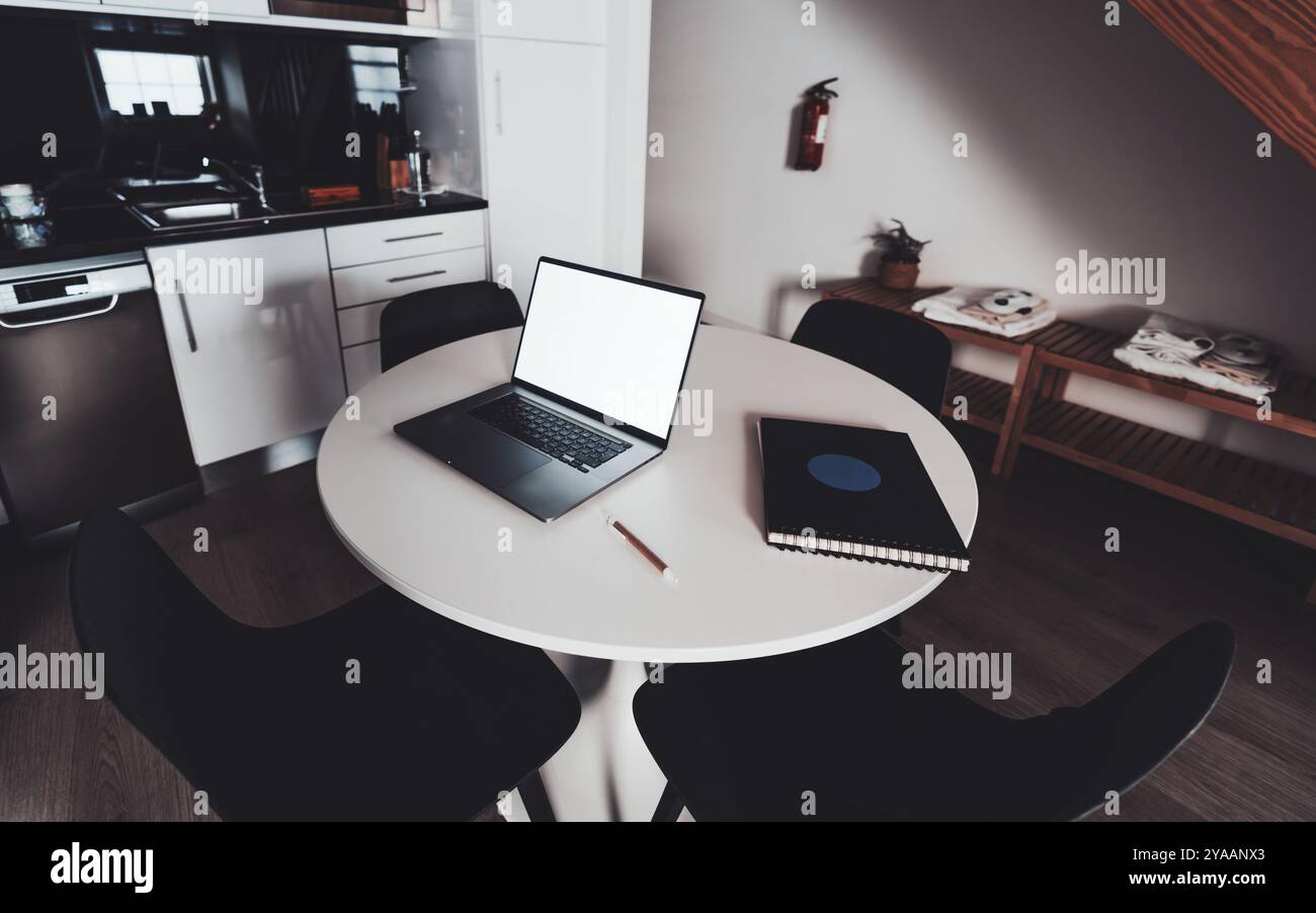 Modern minimalist kitchen with a round table, open laptop, pencil, and ...