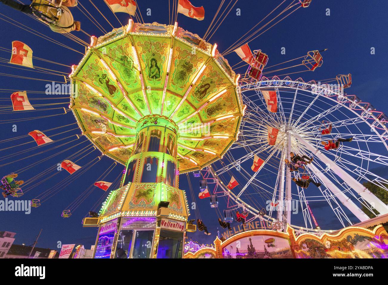Illuminated carousel and Ferris wheel at night in a lively amusement ...