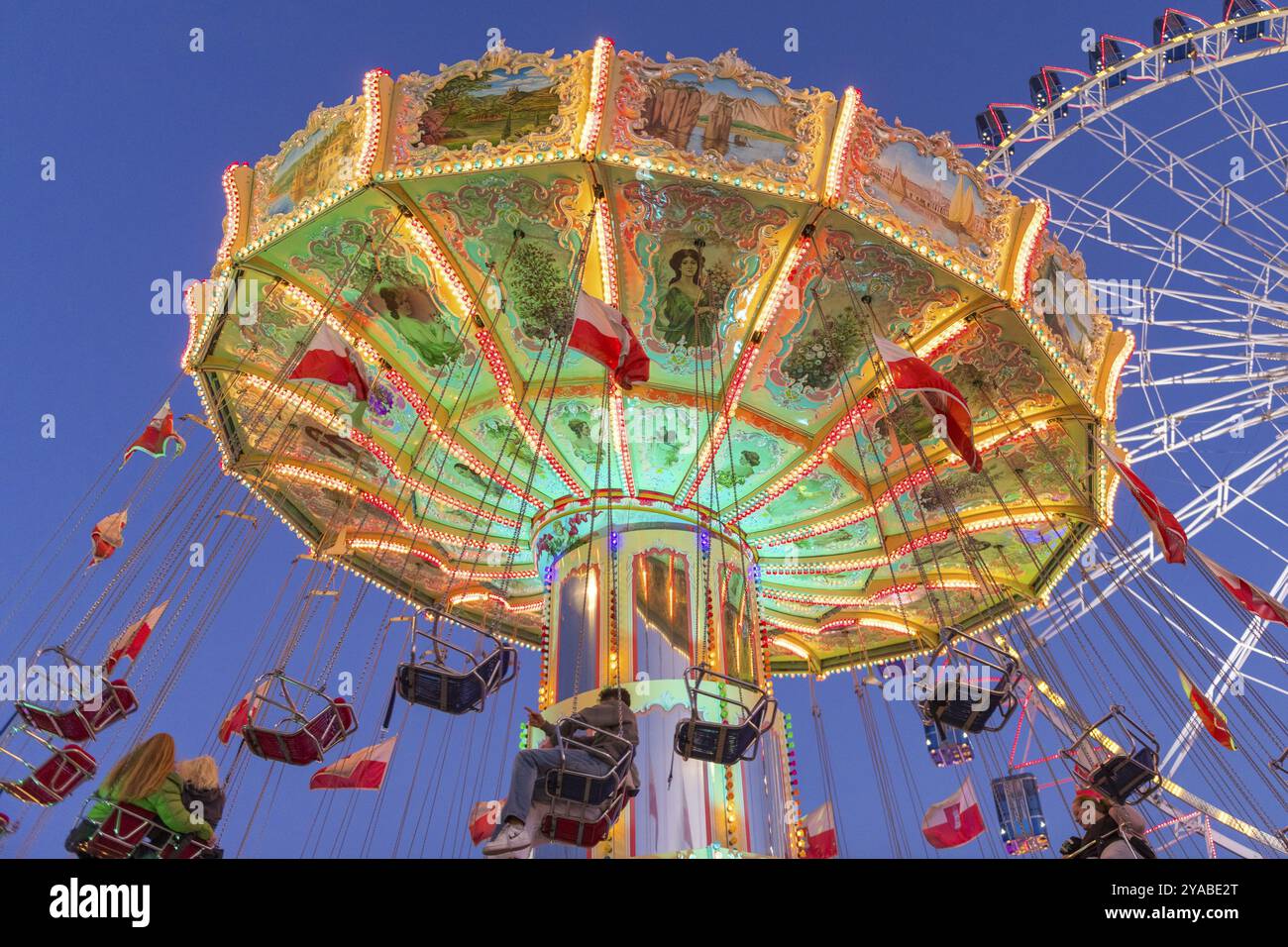 Illuminated carousel and Ferris wheel at night in a lively amusement ...