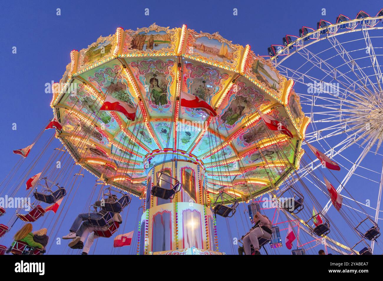 Illuminated carousel and Ferris wheel at night in a lively amusement ...