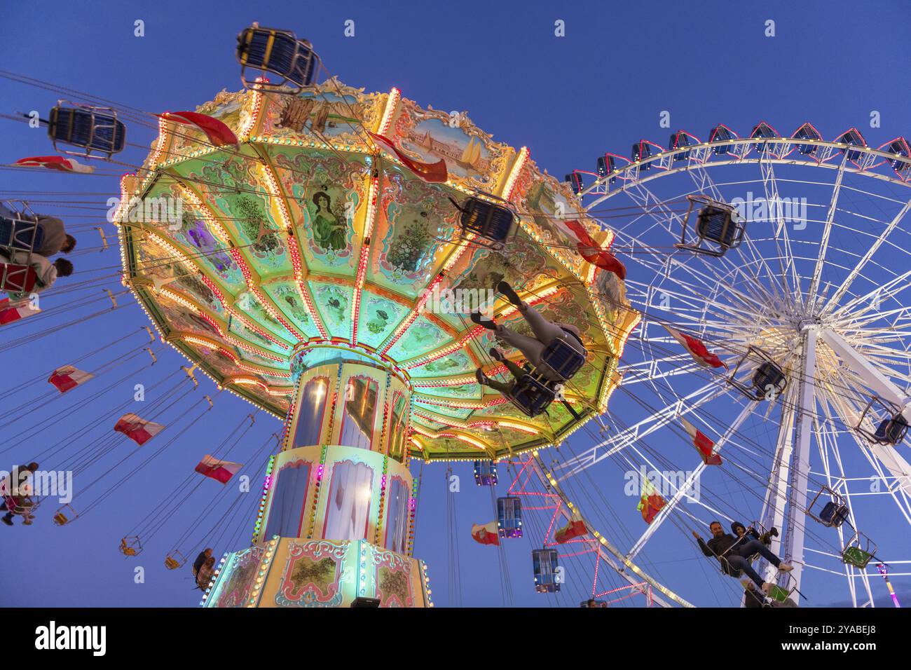 Illuminated carousel and Ferris wheel at night in a lively amusement ...