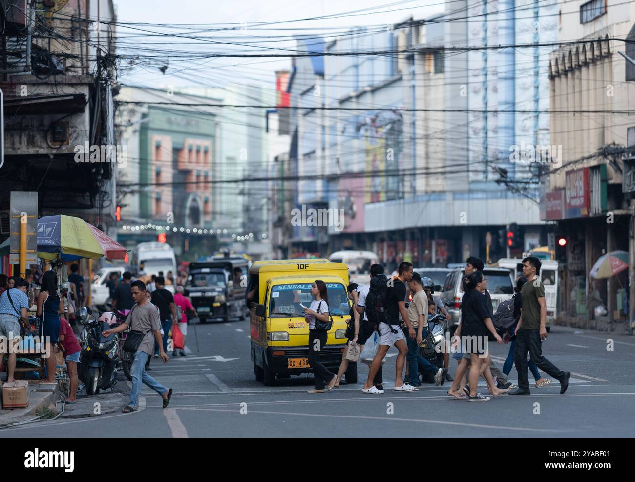 Pedestrians cross Colon Street, Cebu City. In the scene there are ...