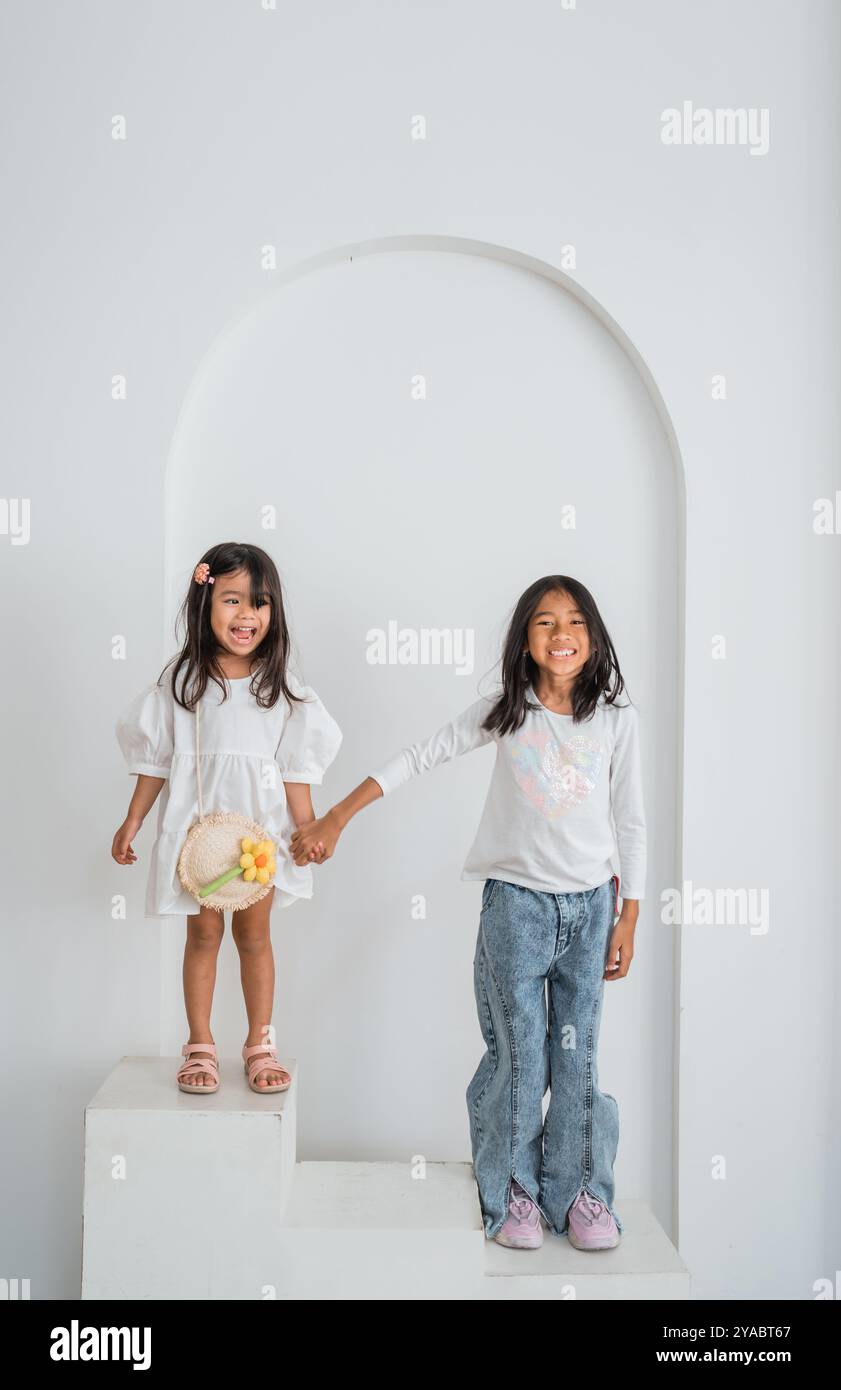 Two little girls joyfully stand together, holding hands tightly Stock ...