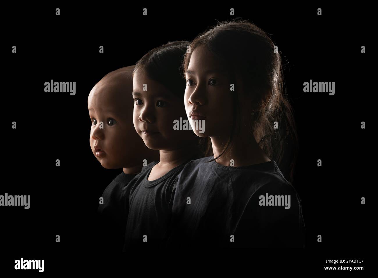 Three children are standing closely together alongside each other in ...