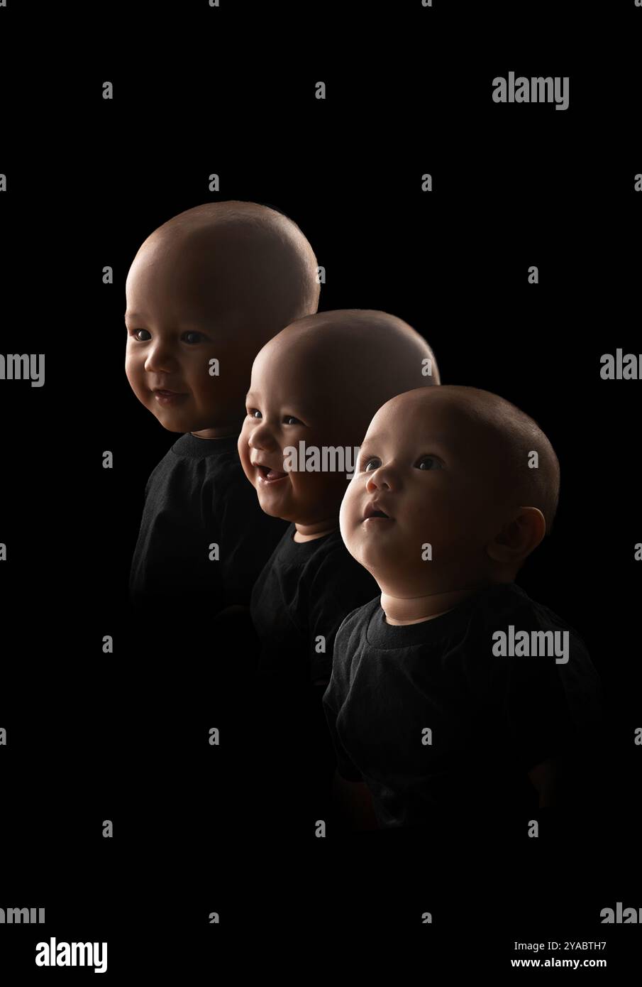 Three babies stand next to each other on a black background Stock Photo ...