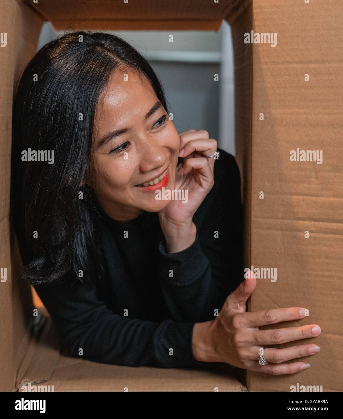 A Playful Woman Playfully Peeking Out from Inside a Cardboard Box with ...
