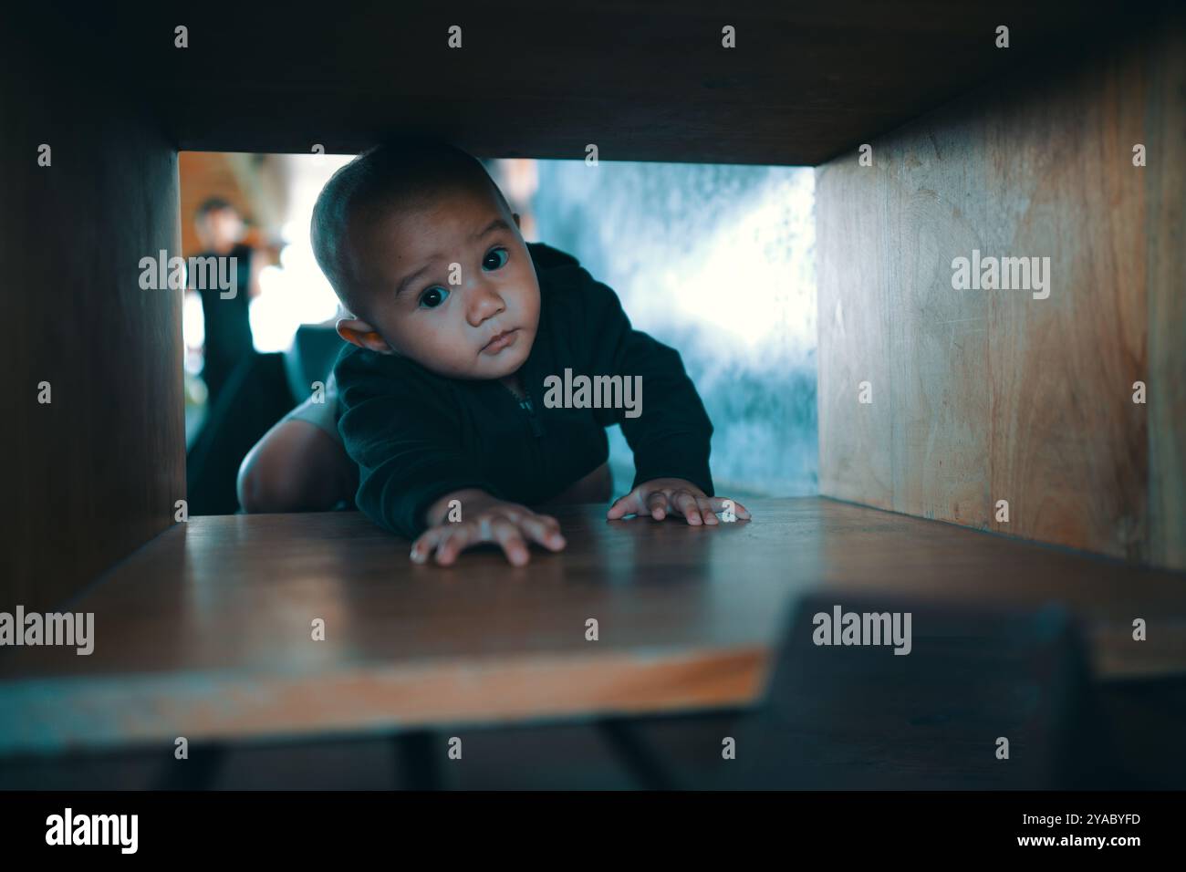 A curious baby happily exploring the small space located beneath the ...