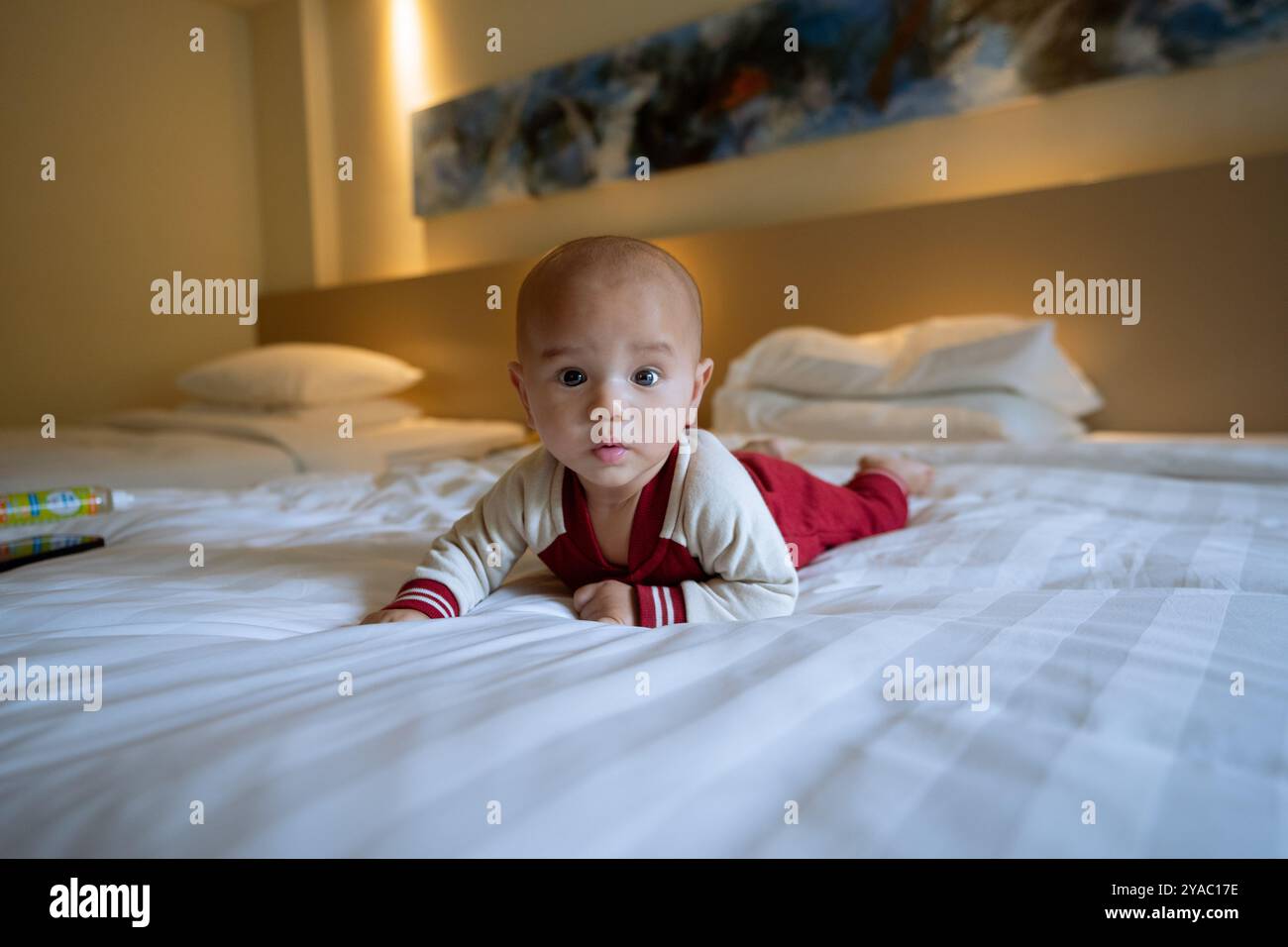 A small baby is laying comfortably on his stomach on a soft bed Stock ...