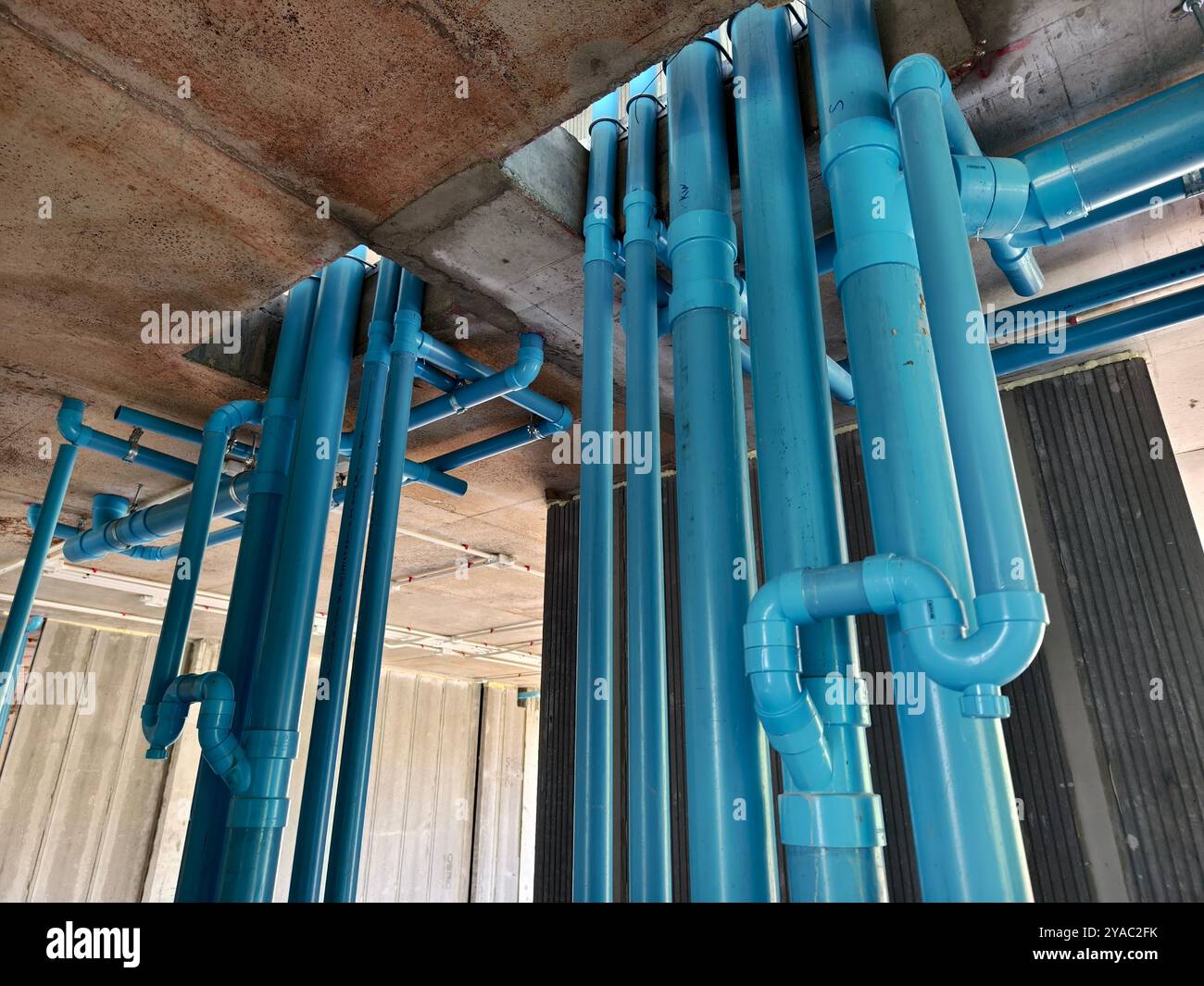 A bright blue pipes attached to a solid concrete wall Stock Photo - Alamy