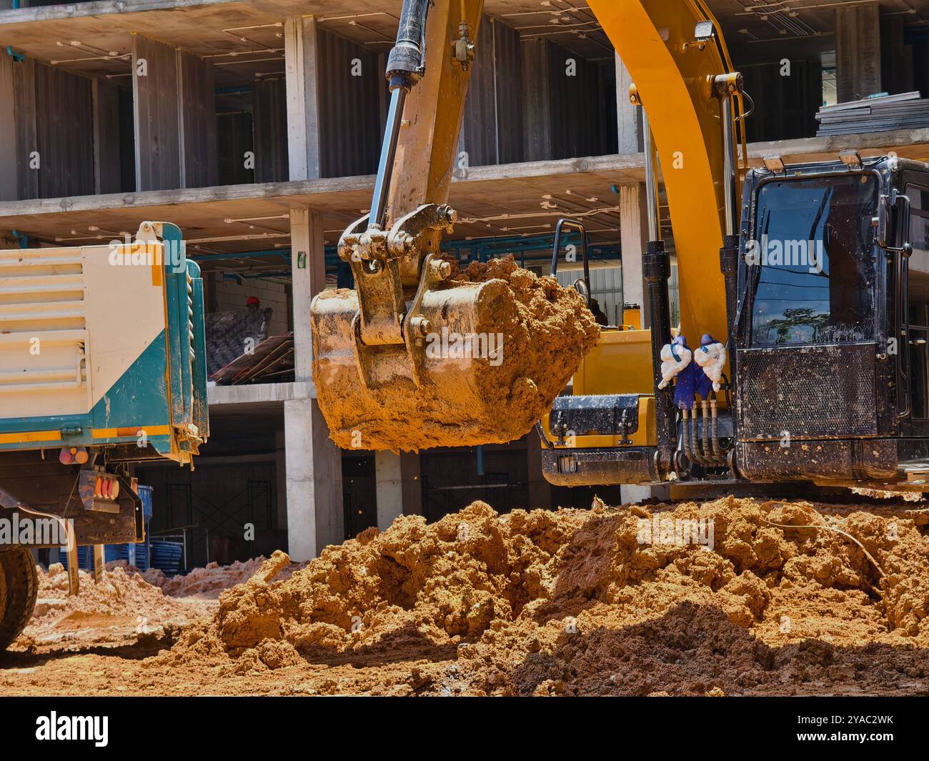 Excavator loads ground into a dump truck at a construction site Stock ...