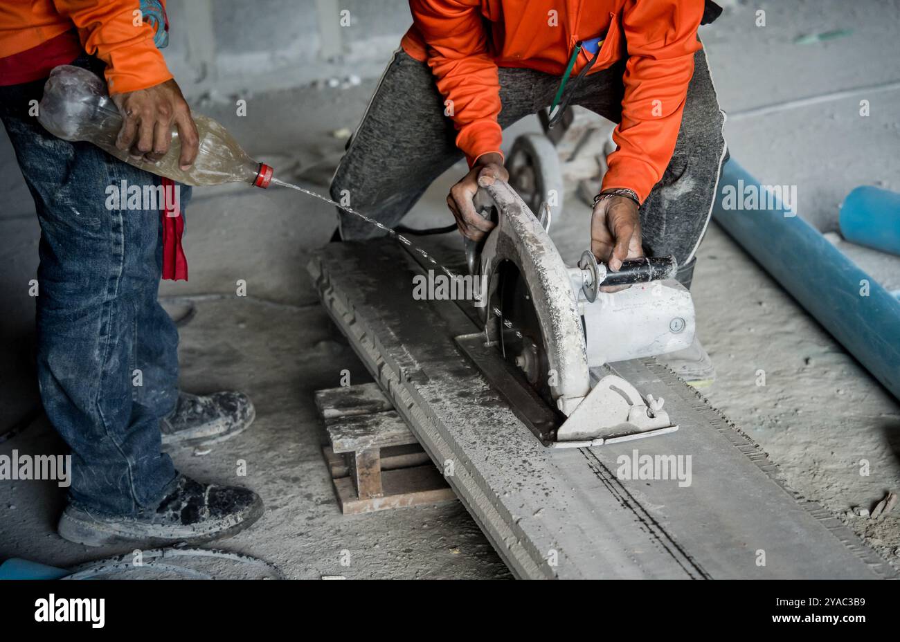 A builder using a circular saw to cut a large concrete piece Stock ...