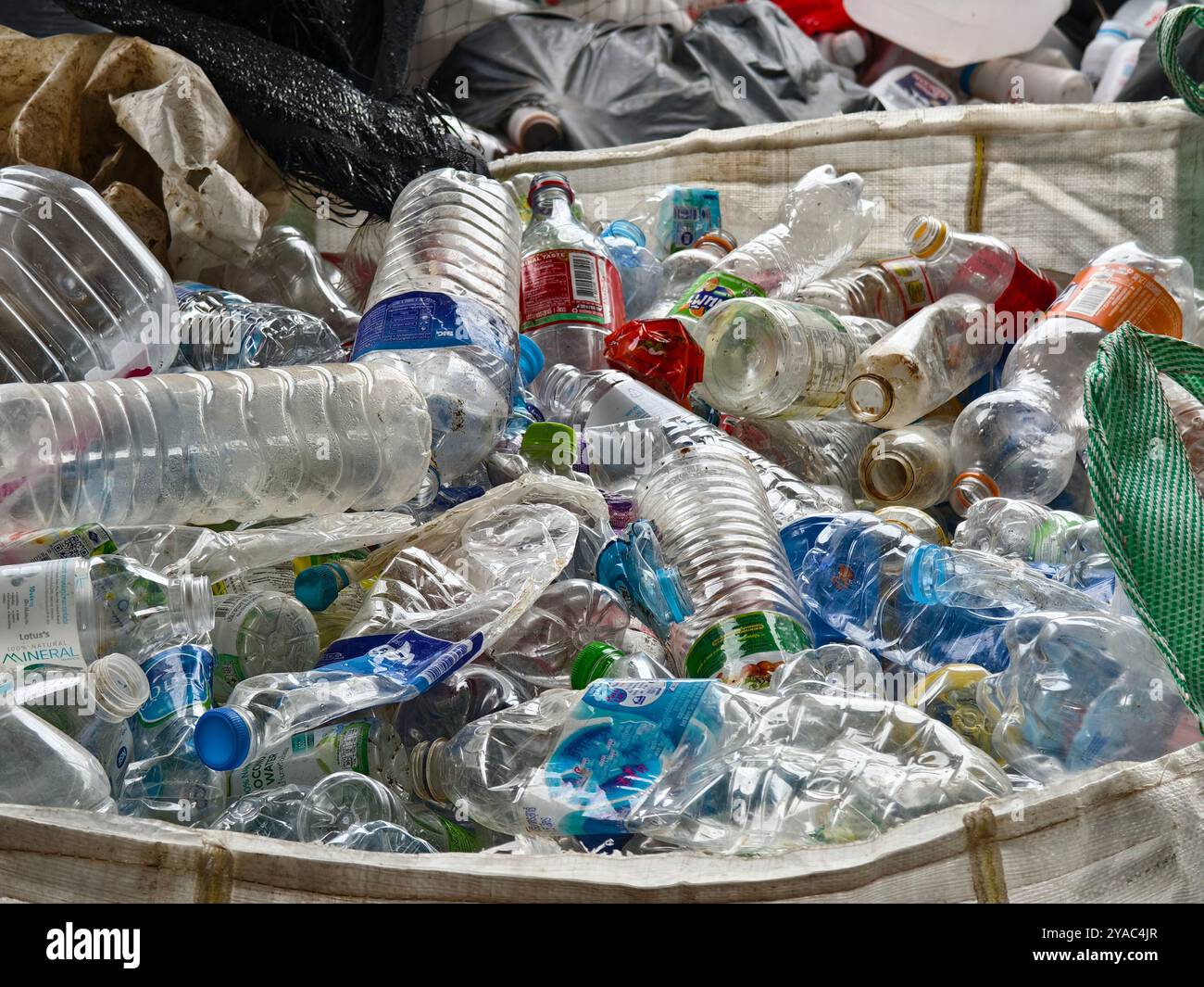 There is a large pile of plastic bottles and cans stored inside a bag ...