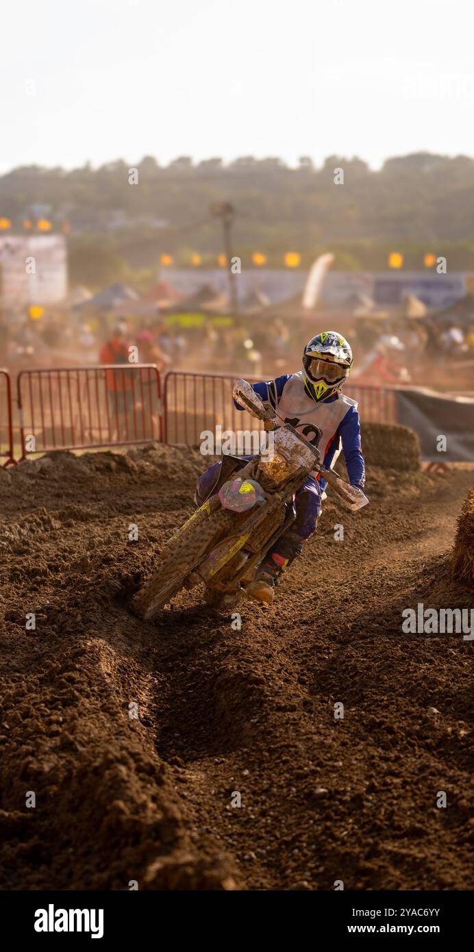 A motocross rider bending into a tight turn on a wet dirt track ...